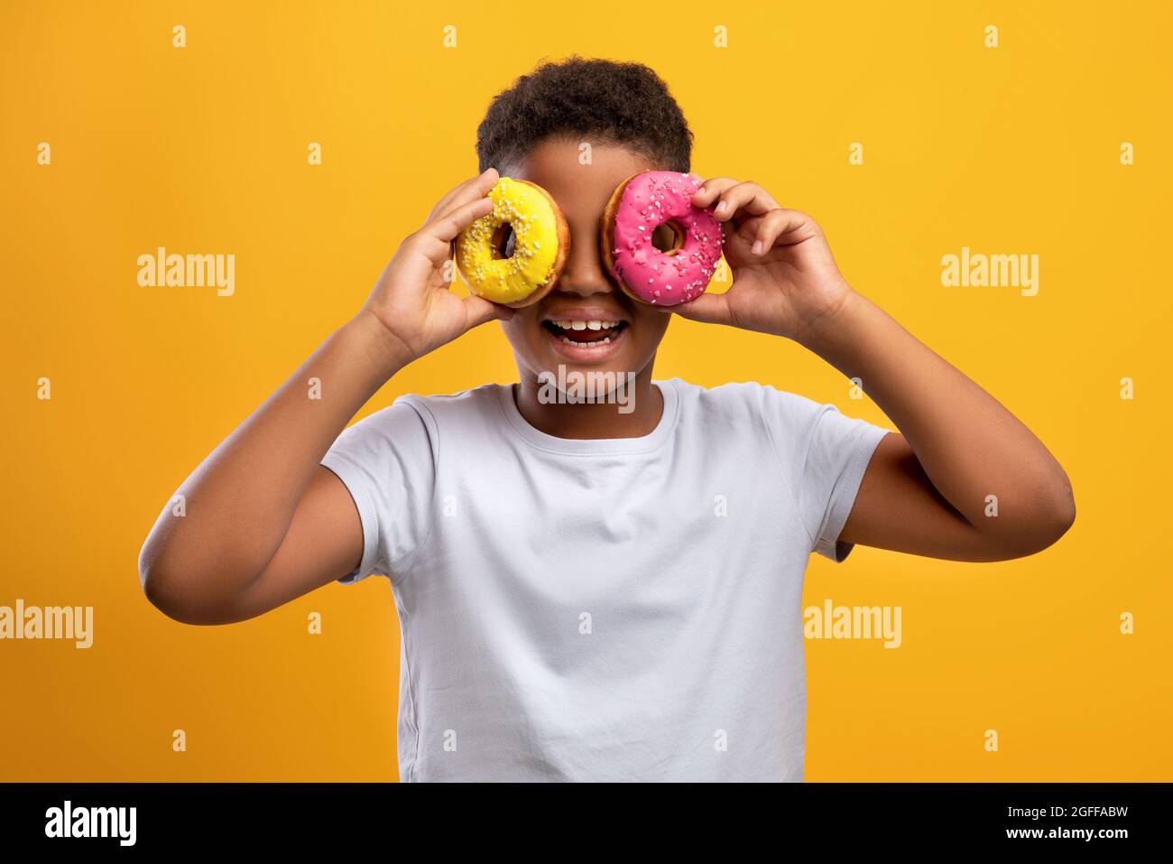 Funny afro american boy holding donuts over eyes Stock Photo - Alamy
