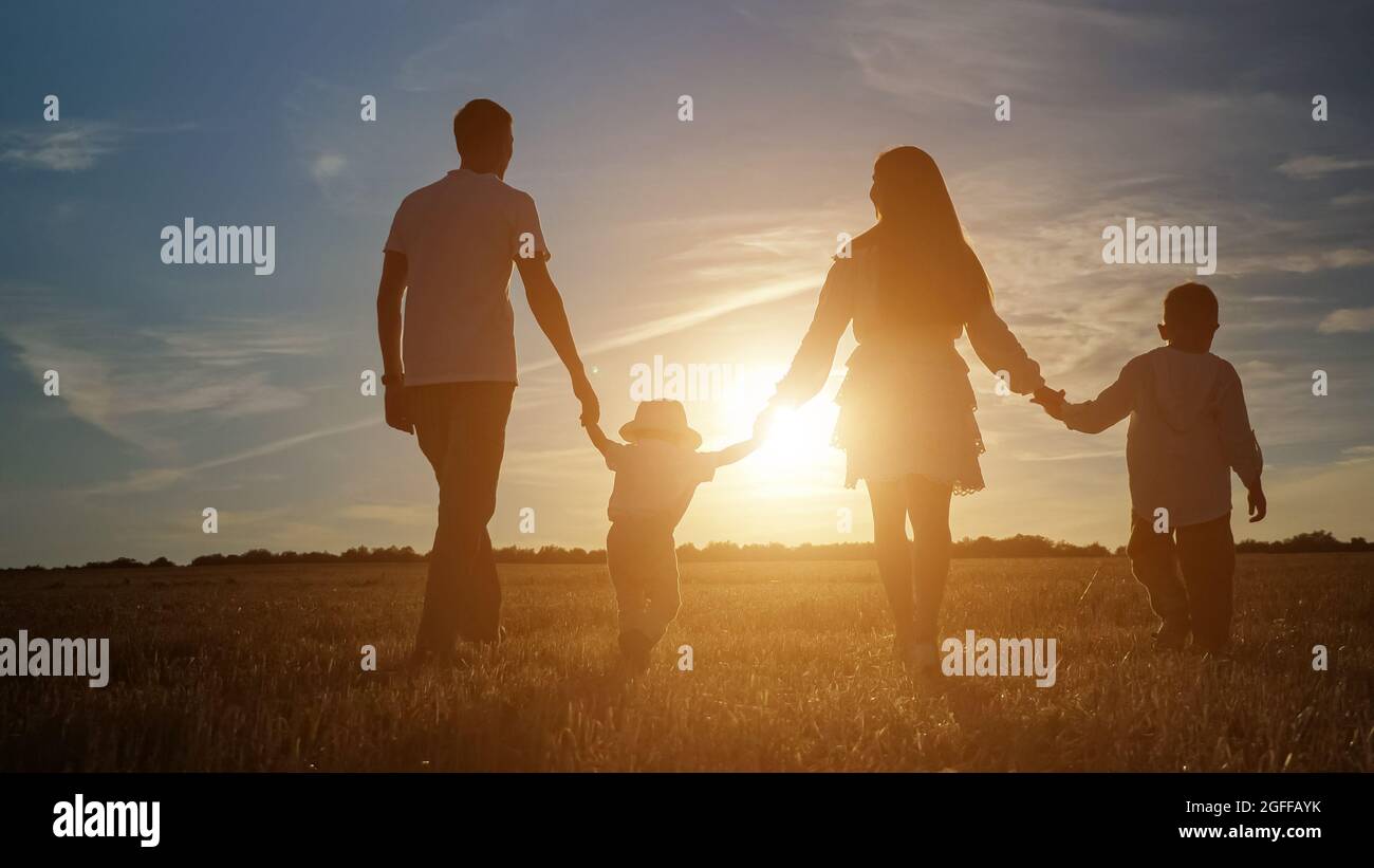 Family with children walks along fields at back setting sun Stock Photo ...
