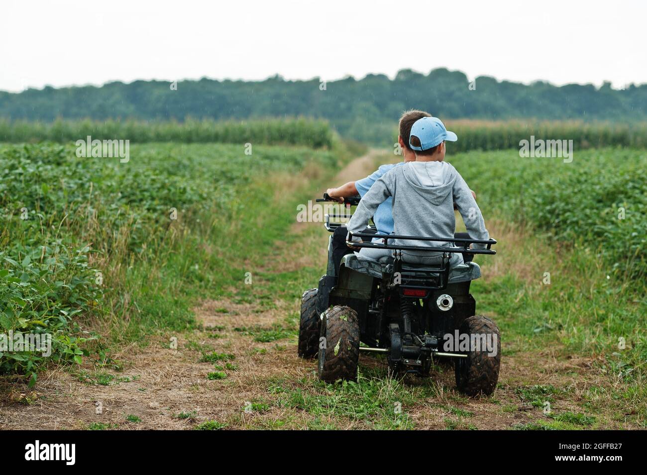 Two brothers driving four-wheller ATV quad bike. Happy children moments ...