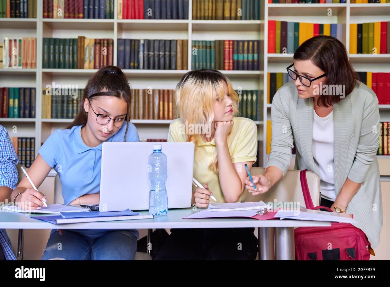 Girls teenage students studying in library with teacher mentor Stock ...