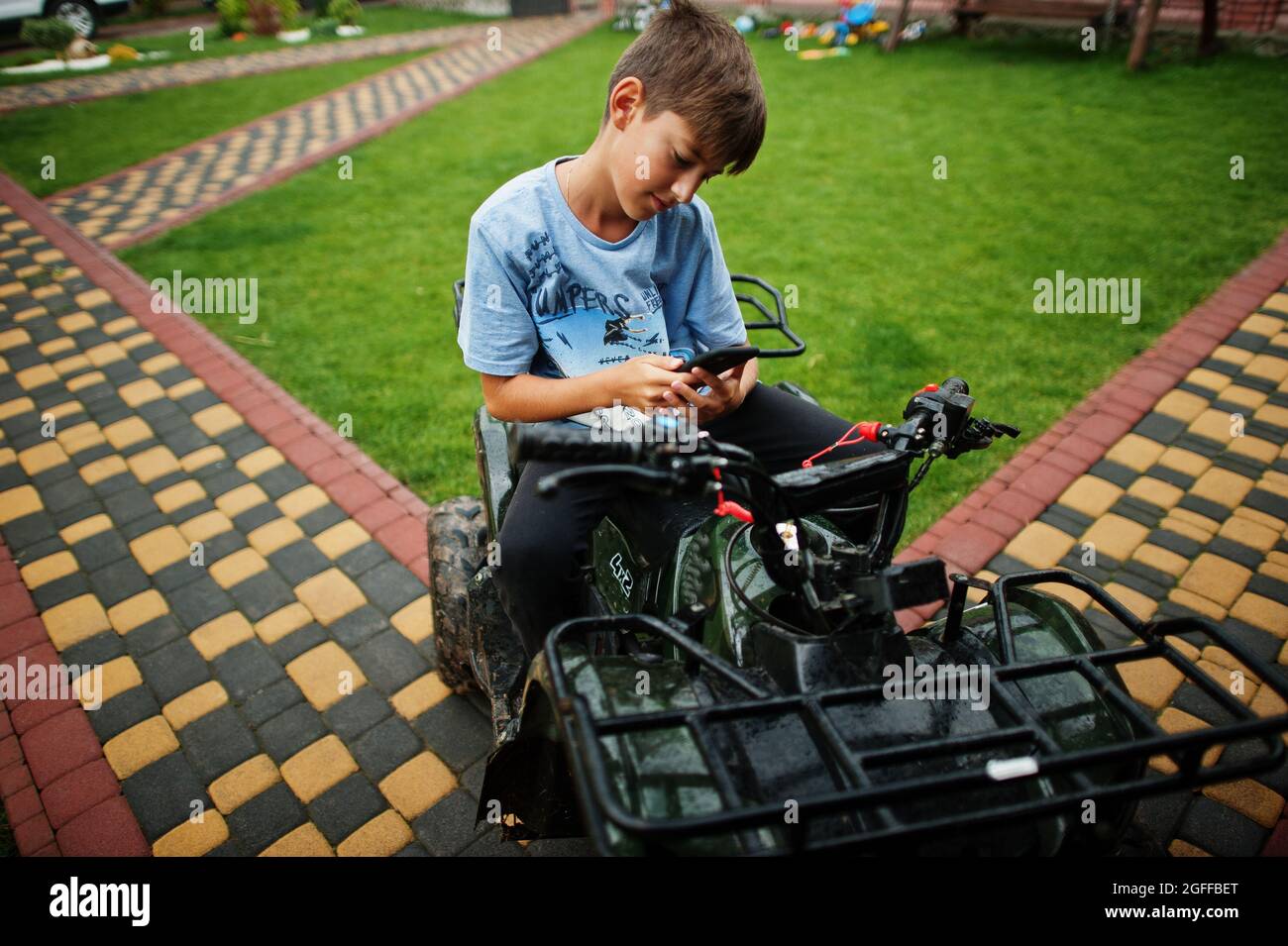 Boy in four-wheller ATV quad bike with mobile phone Stock Photo - Alamy