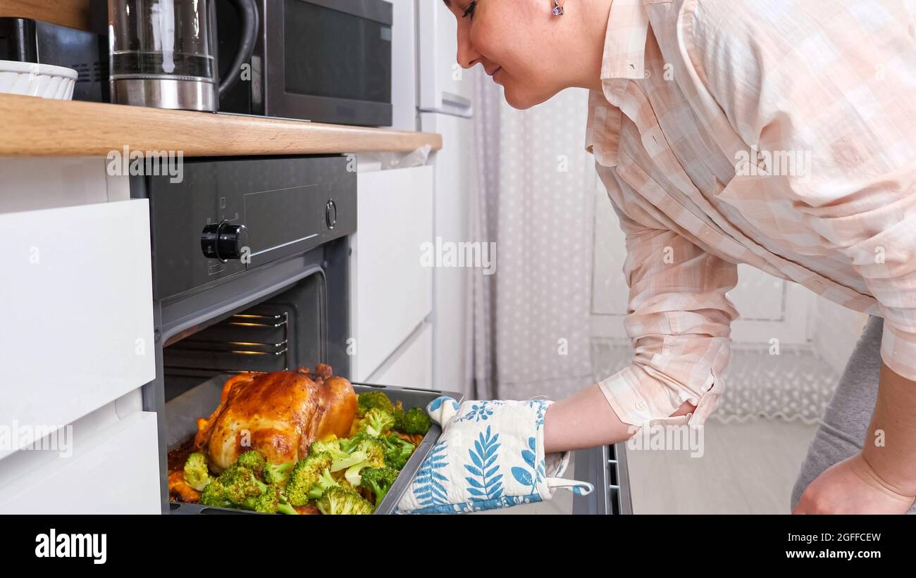 Woman take out crispy chicken on a baking sheet from the oven Stock ...