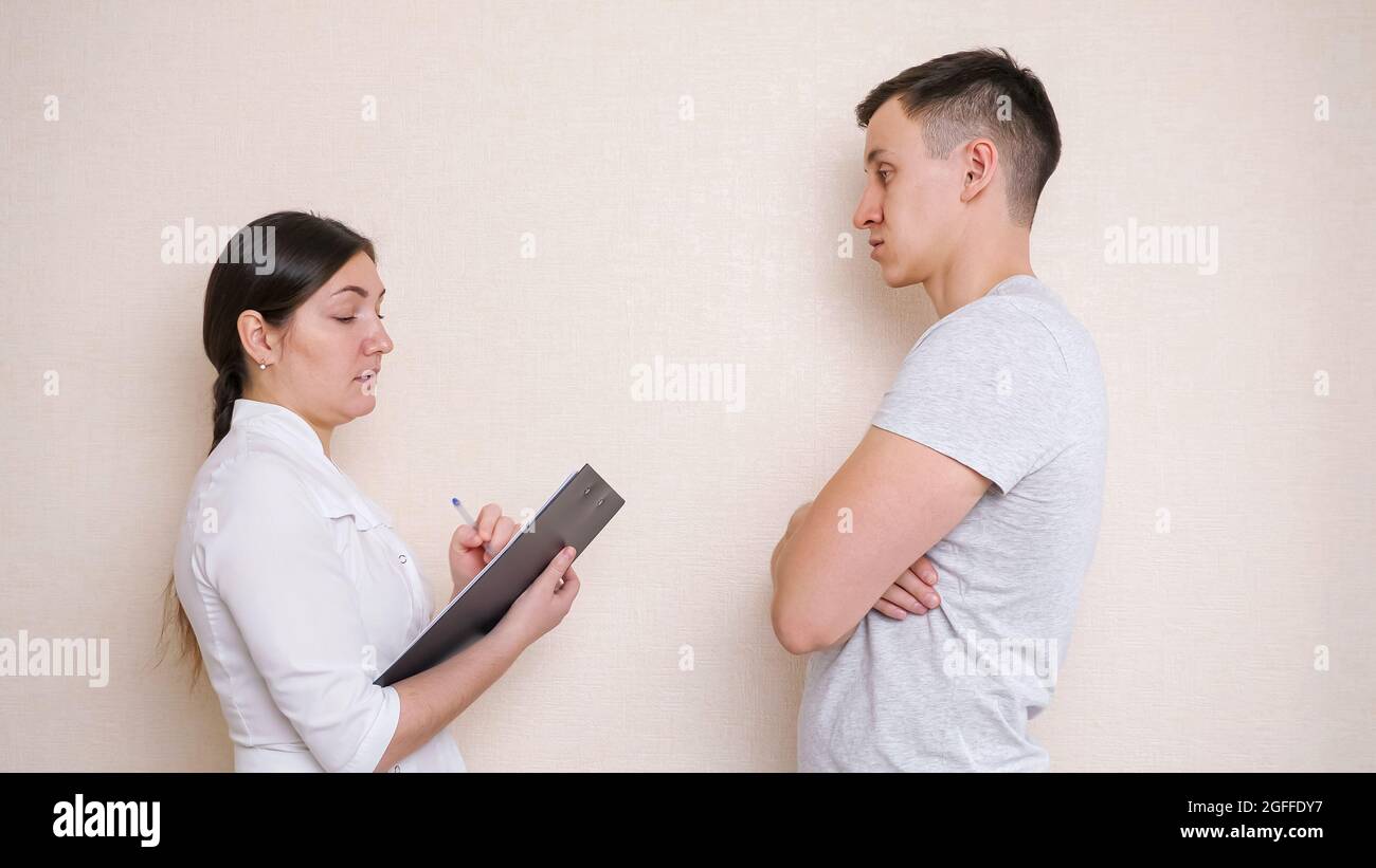 Female doctor interviews a male patient and fills out a document Stock ...