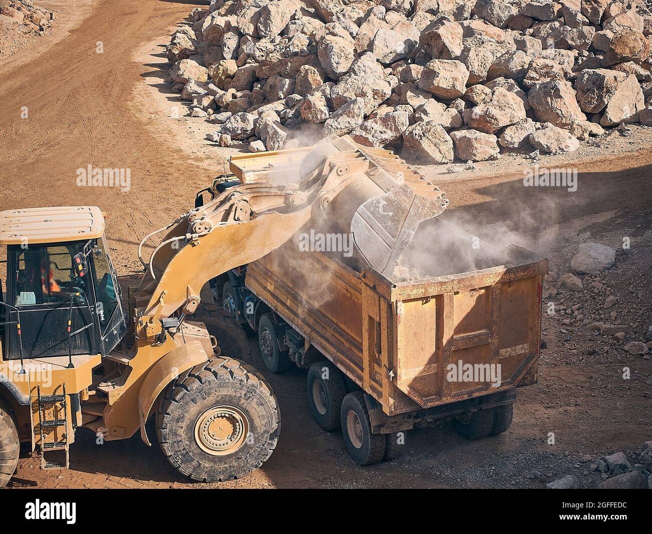 Wheel loader loads tipper with soil Stock Photo - Alamy