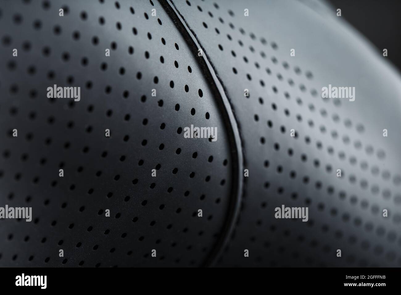 Full-screen close-up of black perforated leather. Texture material in ...