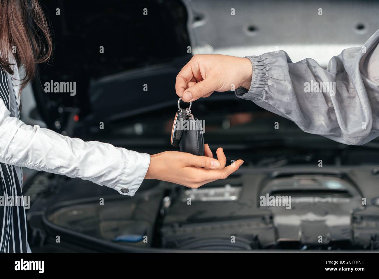 Man giving client keys to her repaired car in auto repair service Stock ...