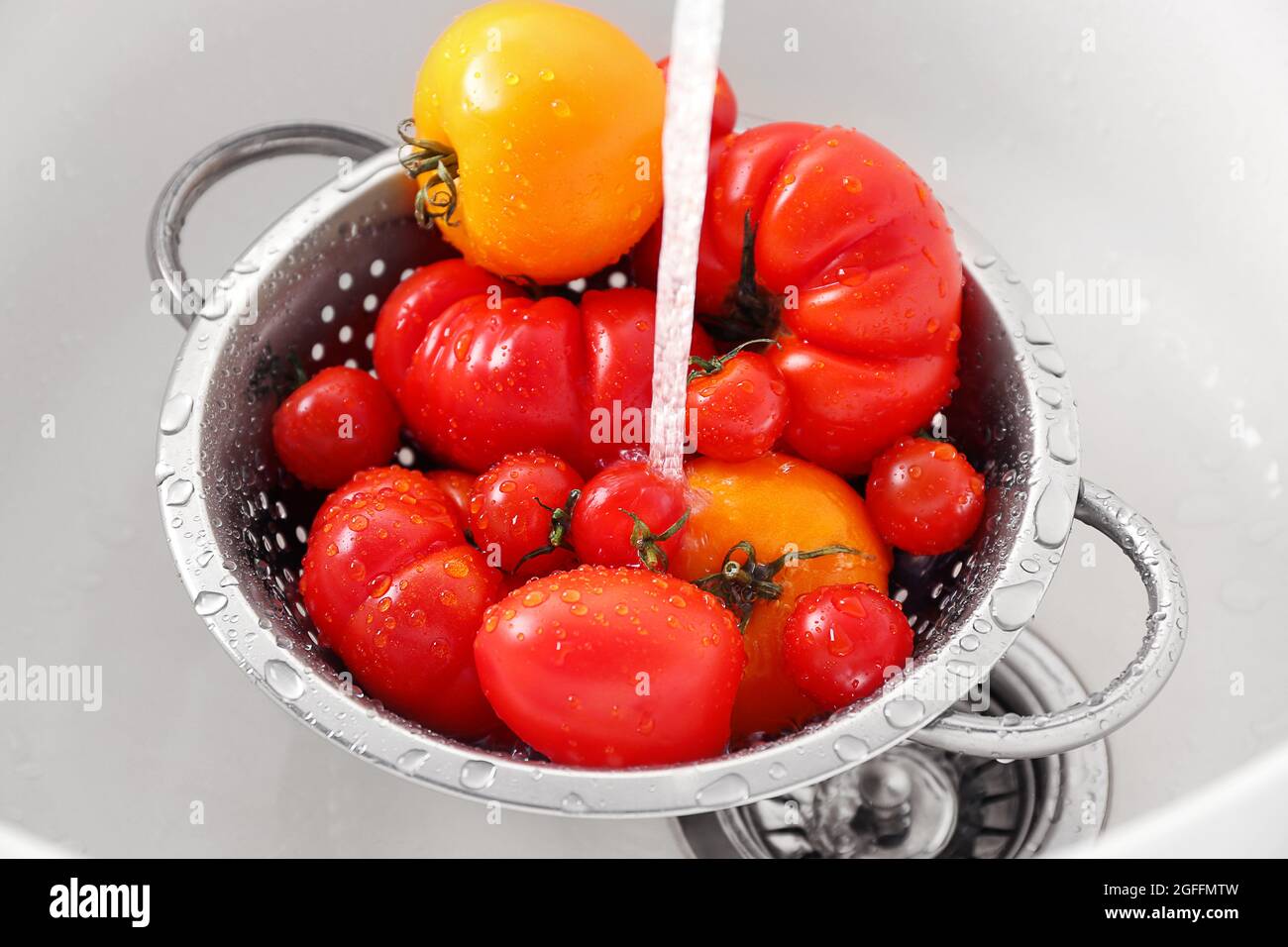 Water flowing into colander with tomatoes in kitchen sink Stock Photo ...