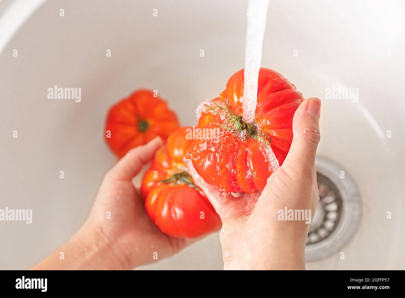 Female hands washing tomatoes in kitchen sink Stock Photo - Alamy