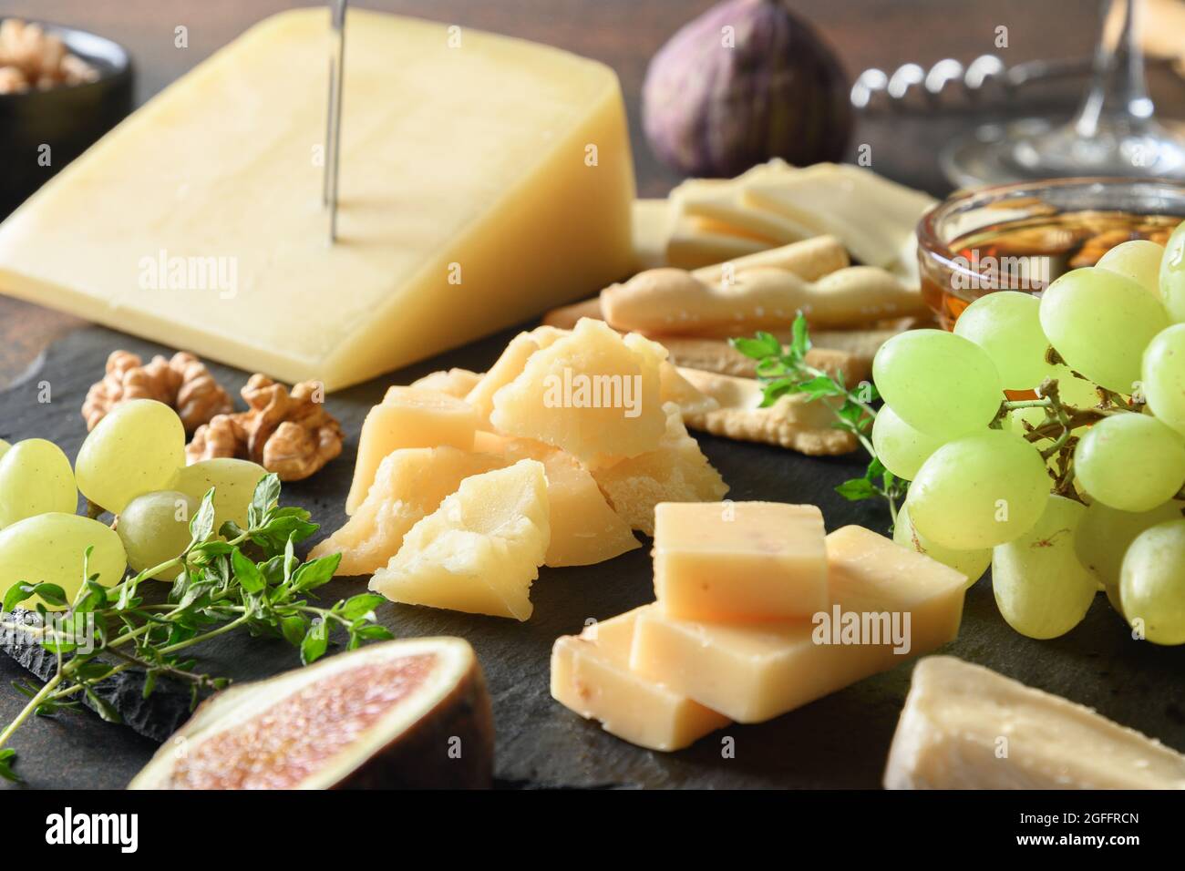 Cheese platter with grapes, nuts, figs on black slate plate. Close up ...