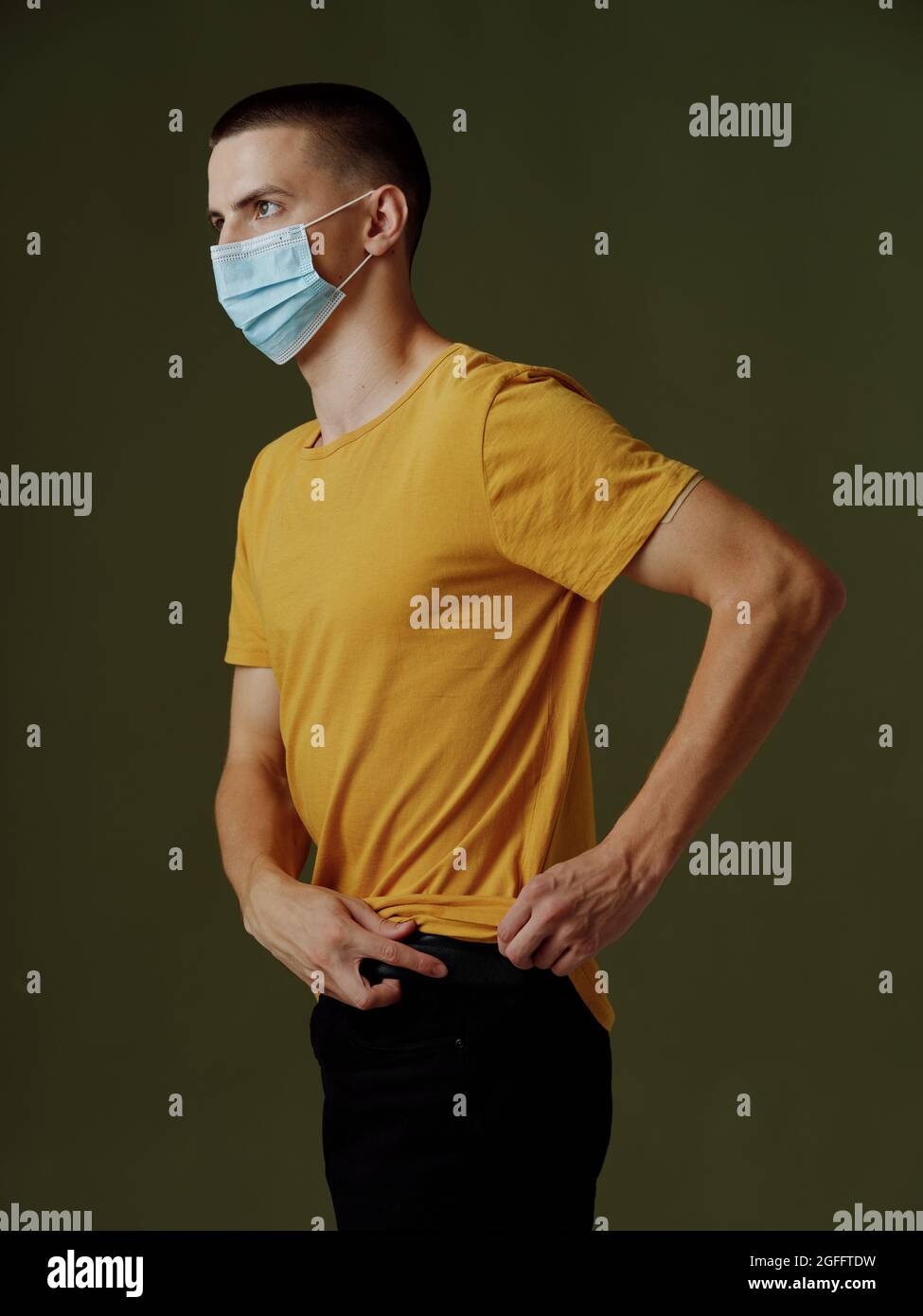 young man in a medical mask with an adhesive plaster on his shoulder ...