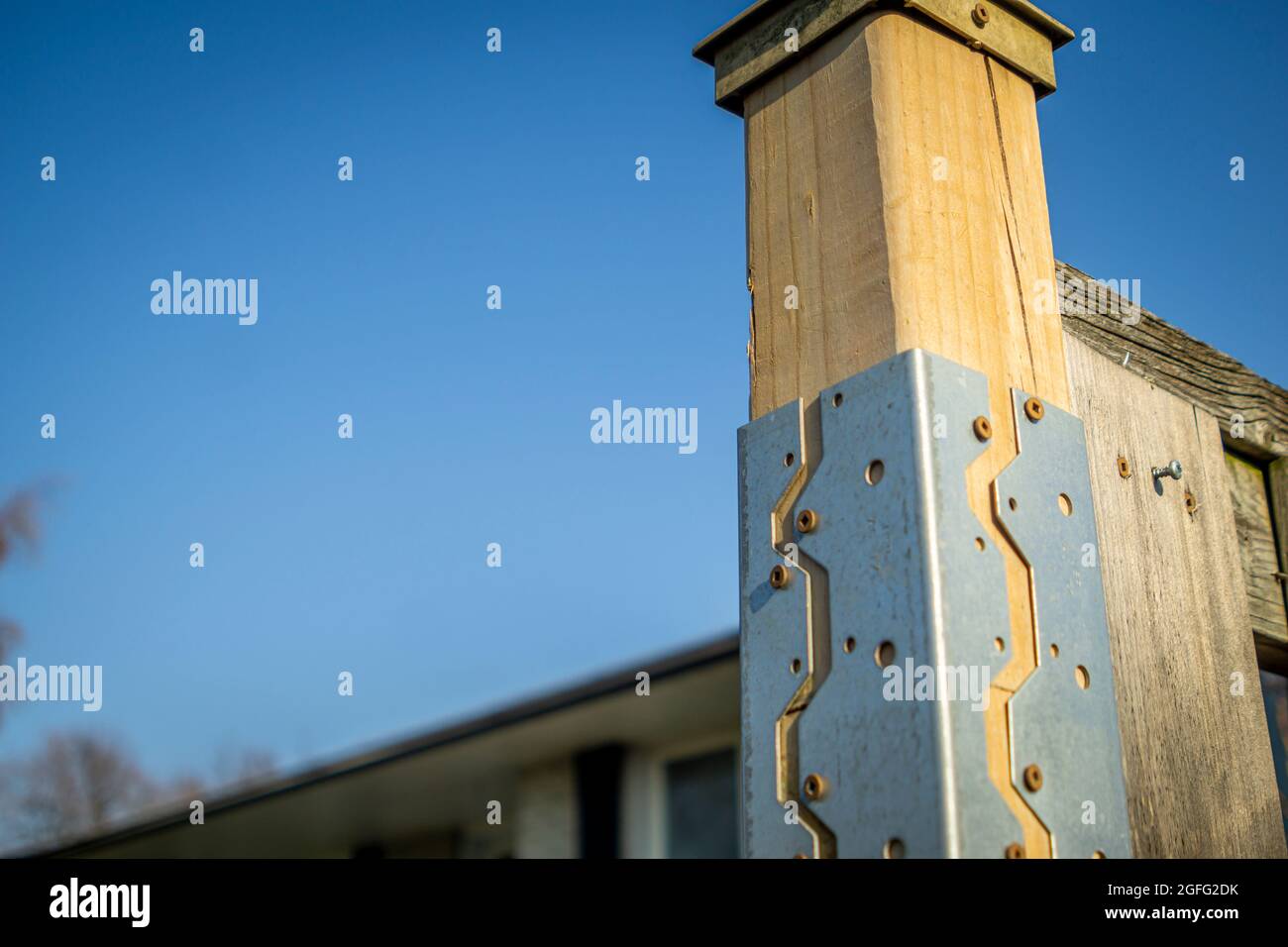 Metal clamp holding an old and dented pole to a wooden fence Stock ...