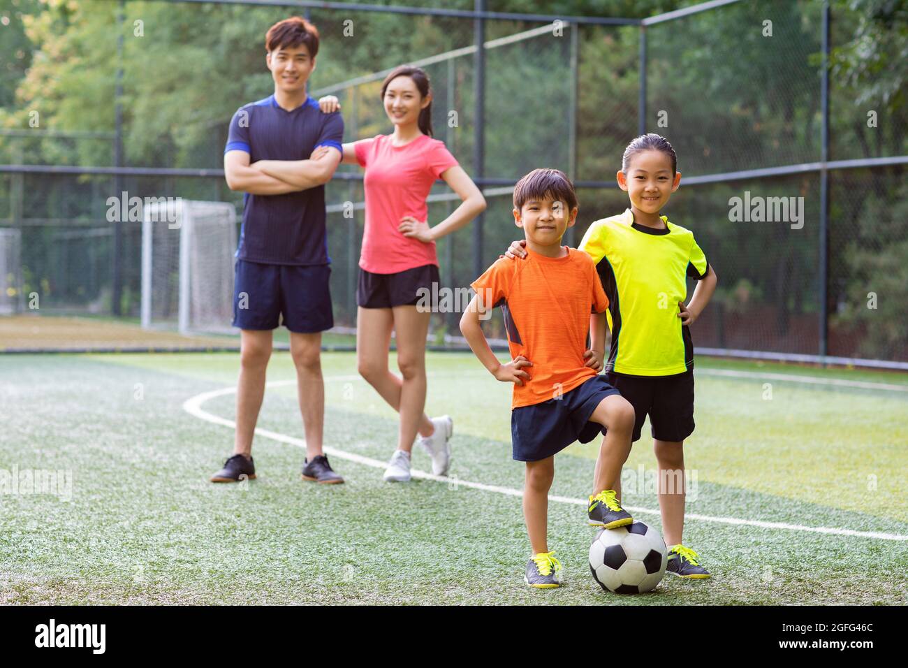 Happy young family playing football on soccer field Stock Photo - Alamy