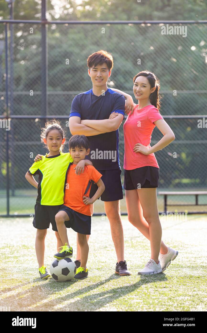 Happy young family playing football on soccer field Stock Photo - Alamy