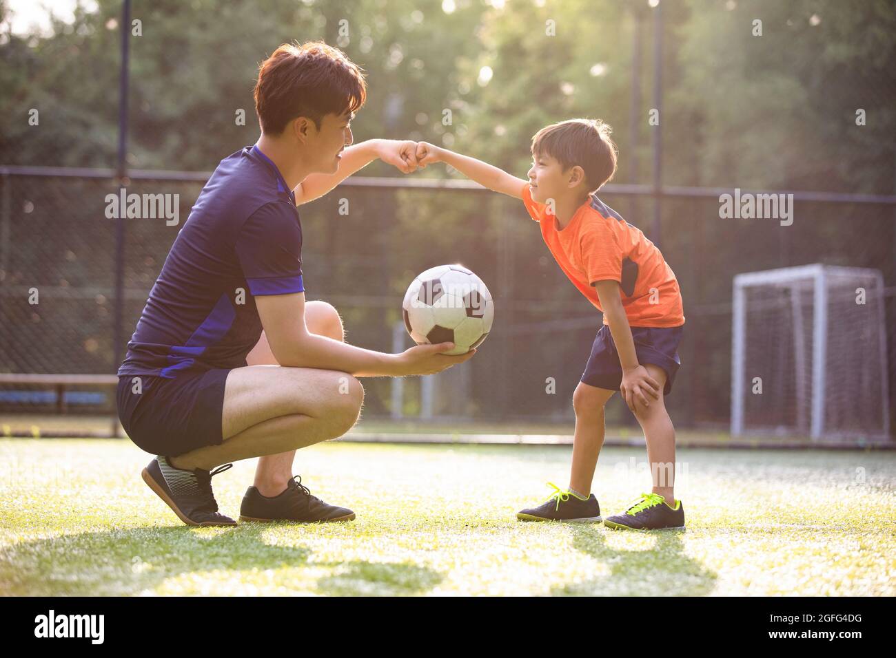 Father and son playing football on field Stock Photo - Alamy