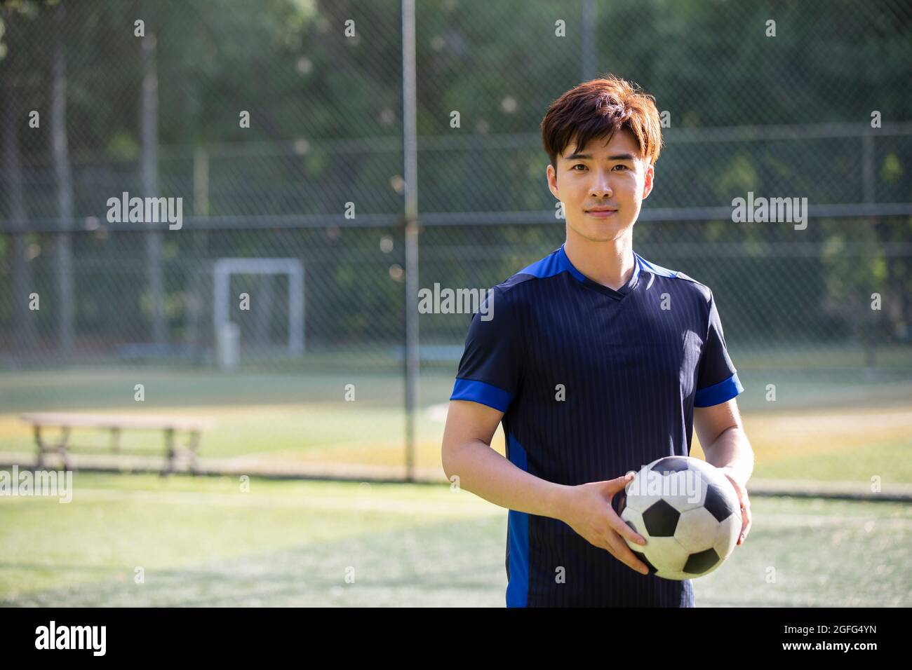 Young man playing football on field Stock Photo - Alamy