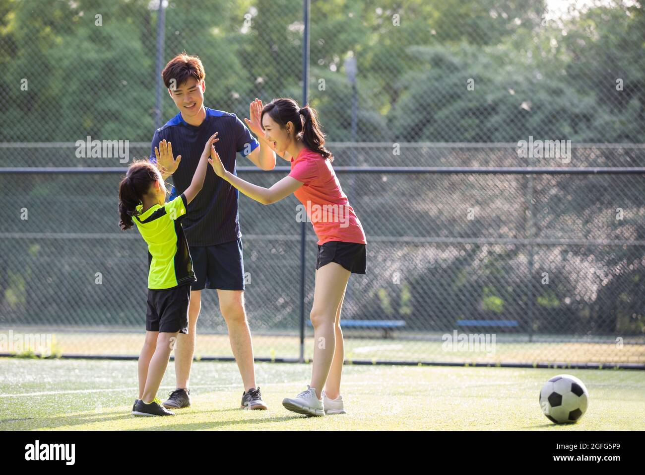 Happy young family playing football on soccer field Stock Photo - Alamy
