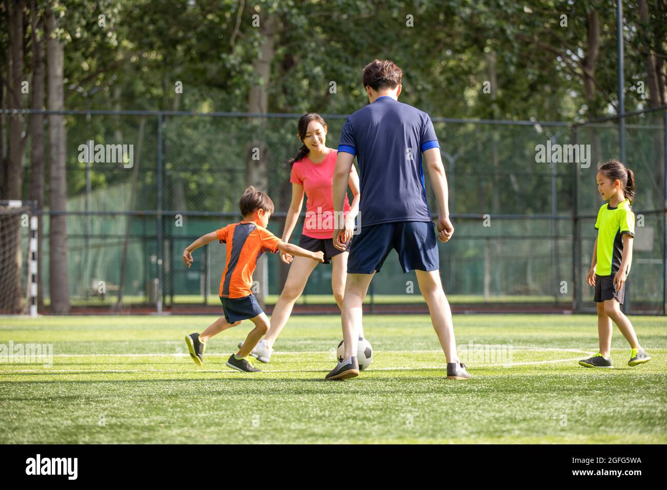 Happy young family playing football on soccer field Stock Photo - Alamy