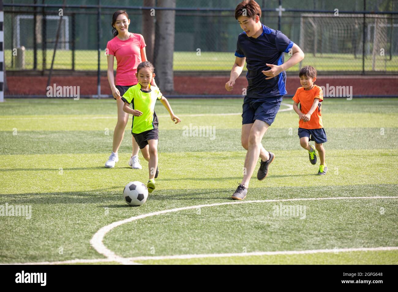 Happy young family playing football on soccer field Stock Photo - Alamy