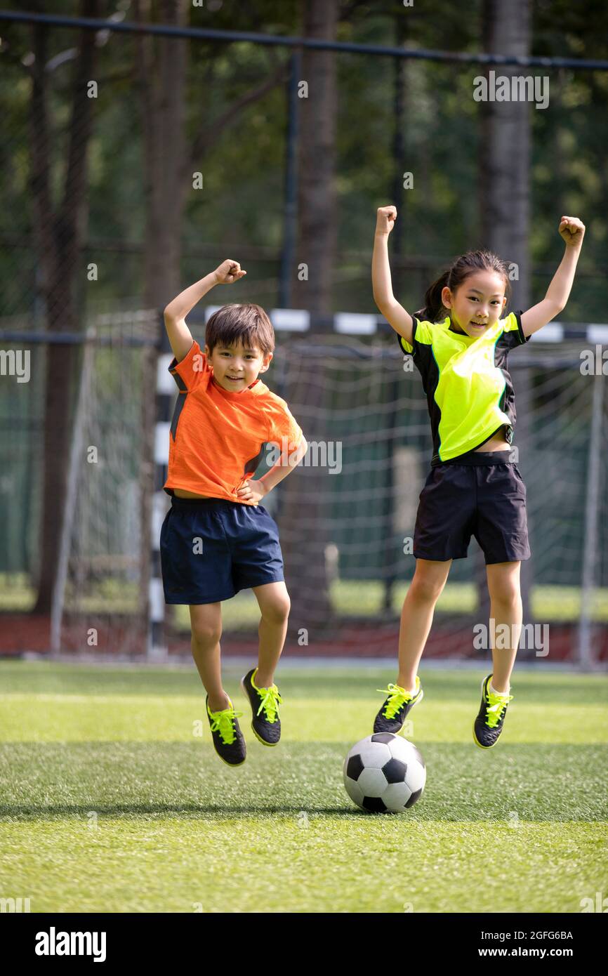 Happy children playing football on field Stock Photo - Alamy