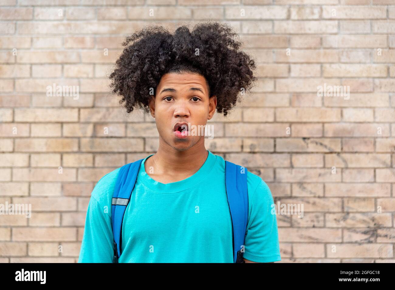 Afro latin male teenager doing a strange face against a wall Stock ...