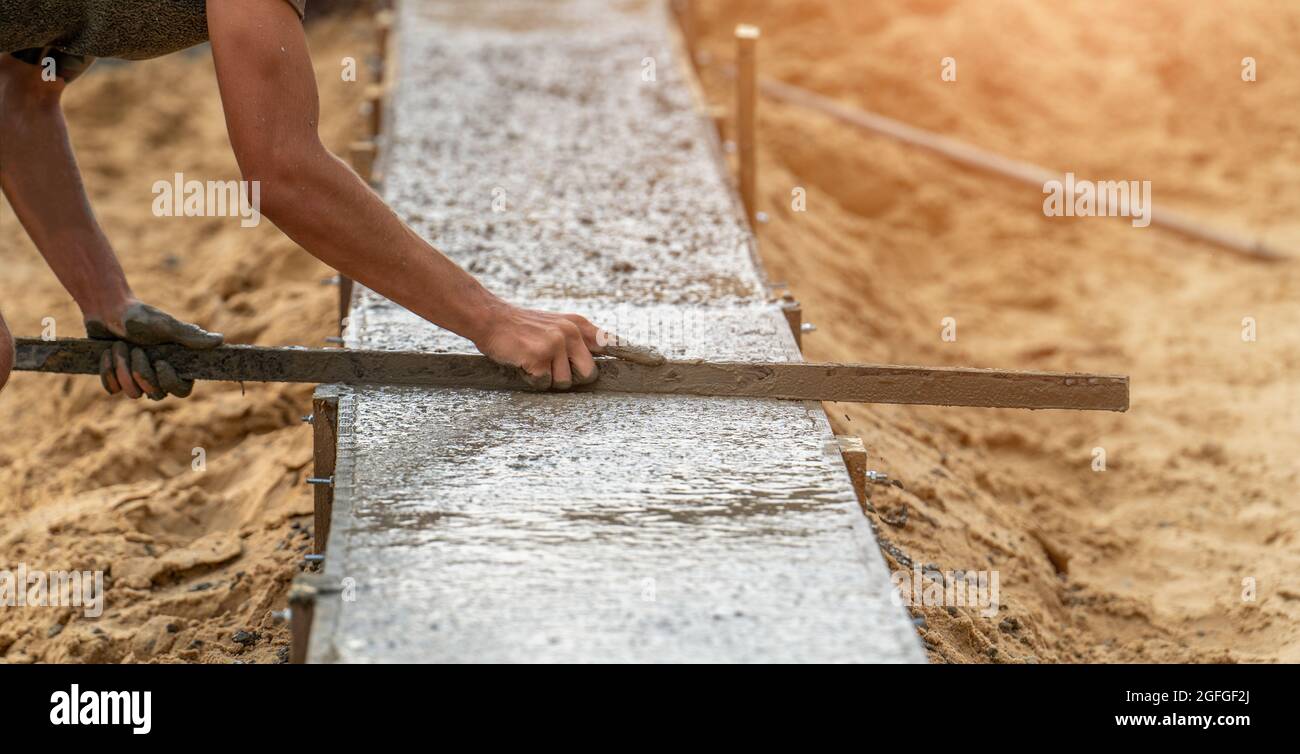 Worker leveling newly poured cement into formwork with reinforcement ...