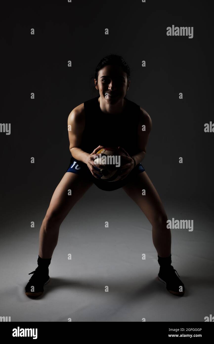 Handball player posing on dark gray background. Girl posing with ball ...