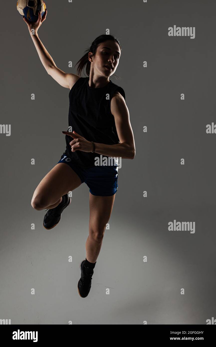 Handball player posing on gray background. Girl jumping with ball Stock ...