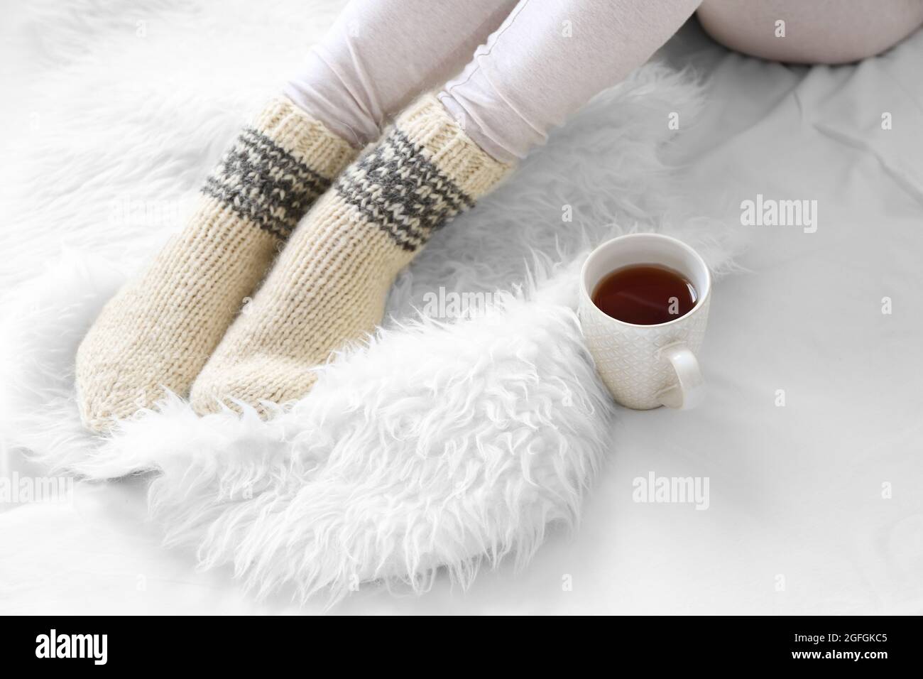 Female feet in socks with cup of tea on bed Stock Photo - Alamy