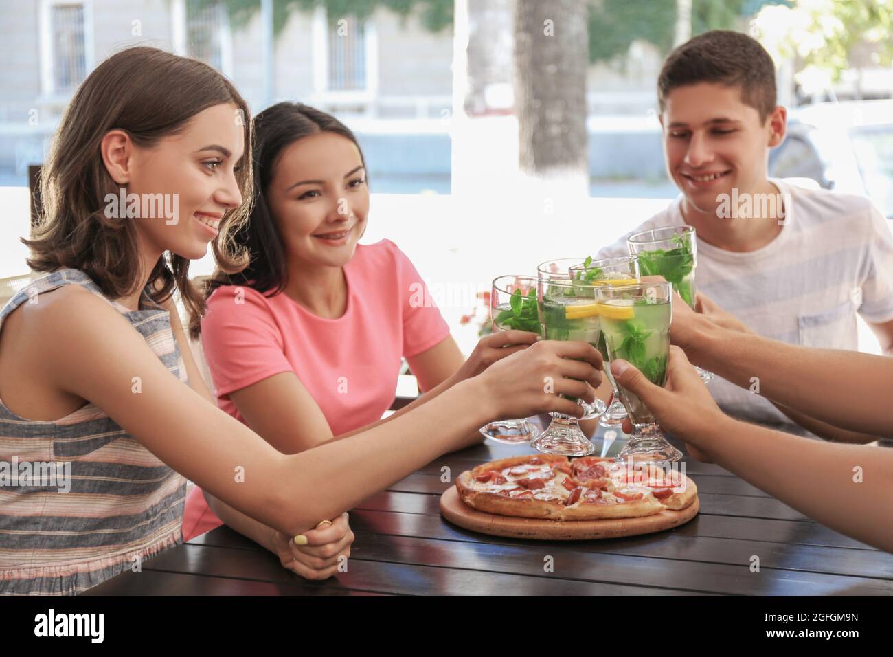 Happy friends eating pizza in cafe Stock Photo - Alamy