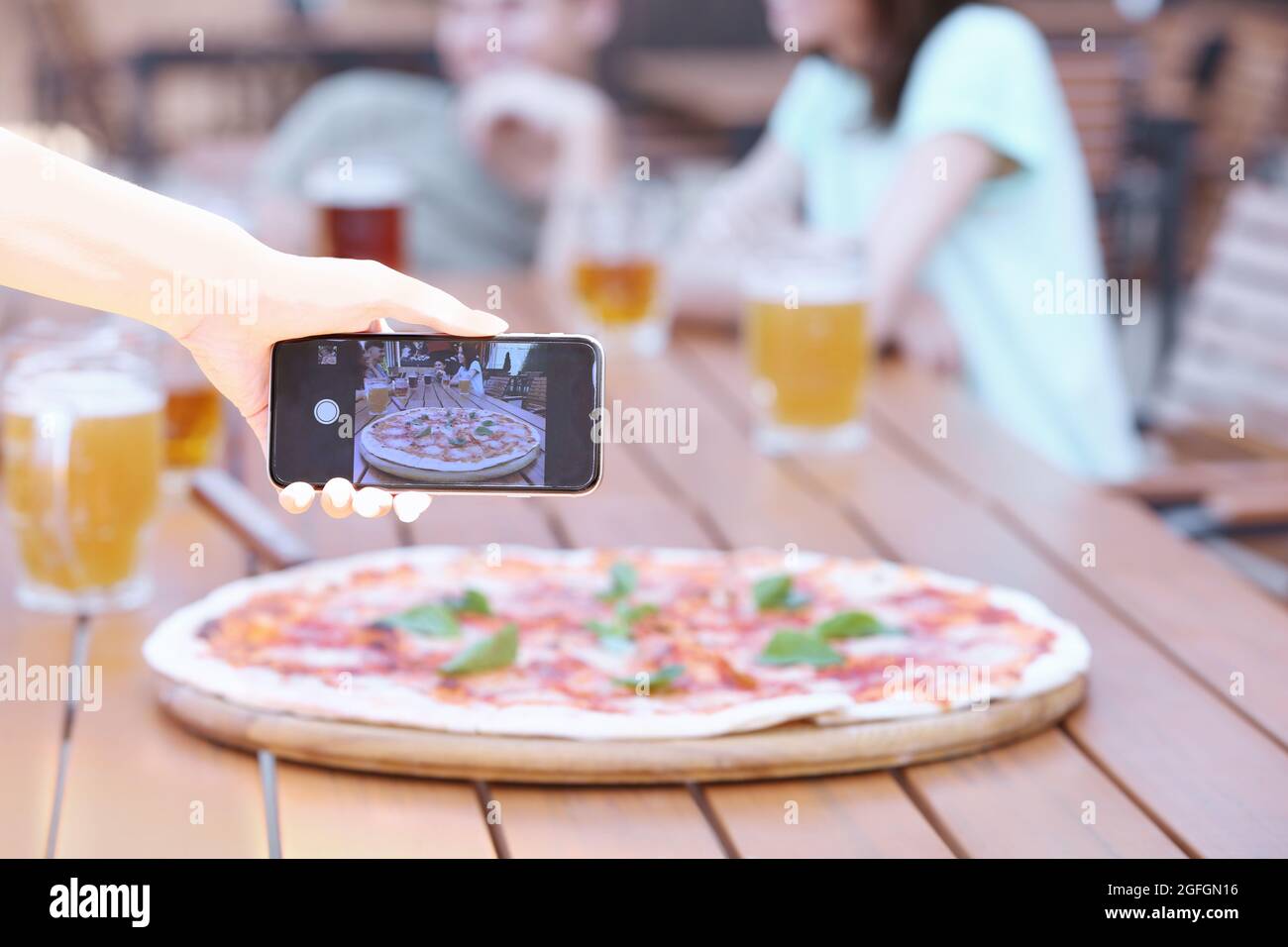 Girl making photo of pizza in cafe Stock Photo - Alamy