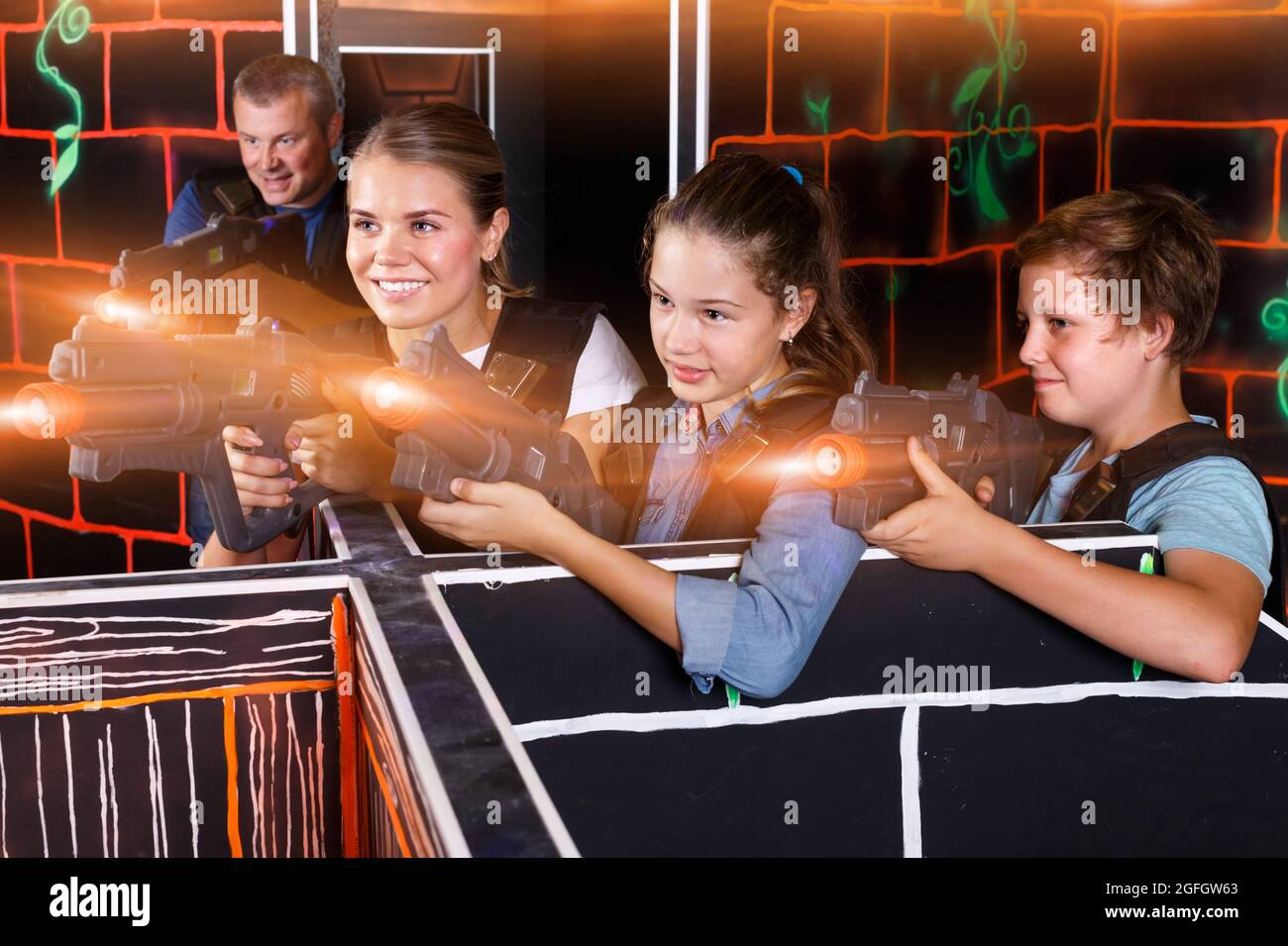 Smiling boy and girls aiming laser guns and playing laser tag ga Stock ...