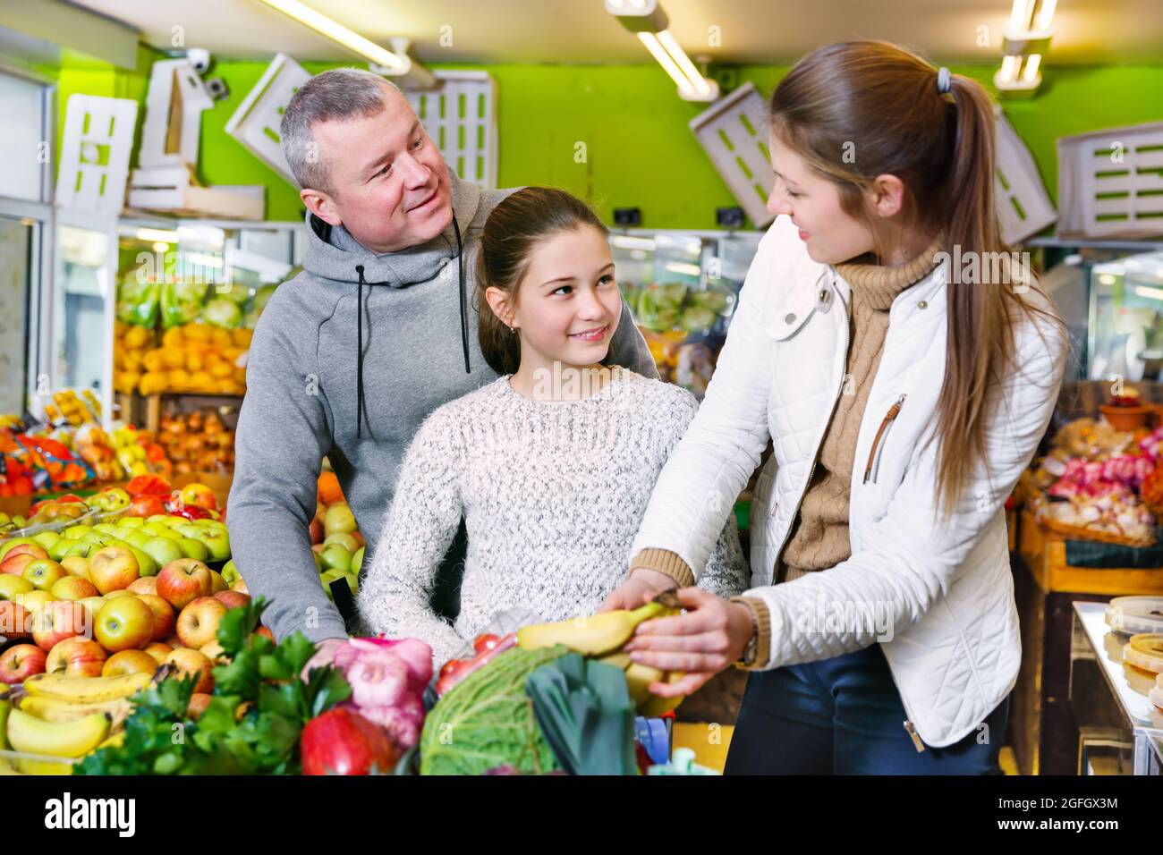Parents with daughter choosing sweet bananas in fruit market Stock ...