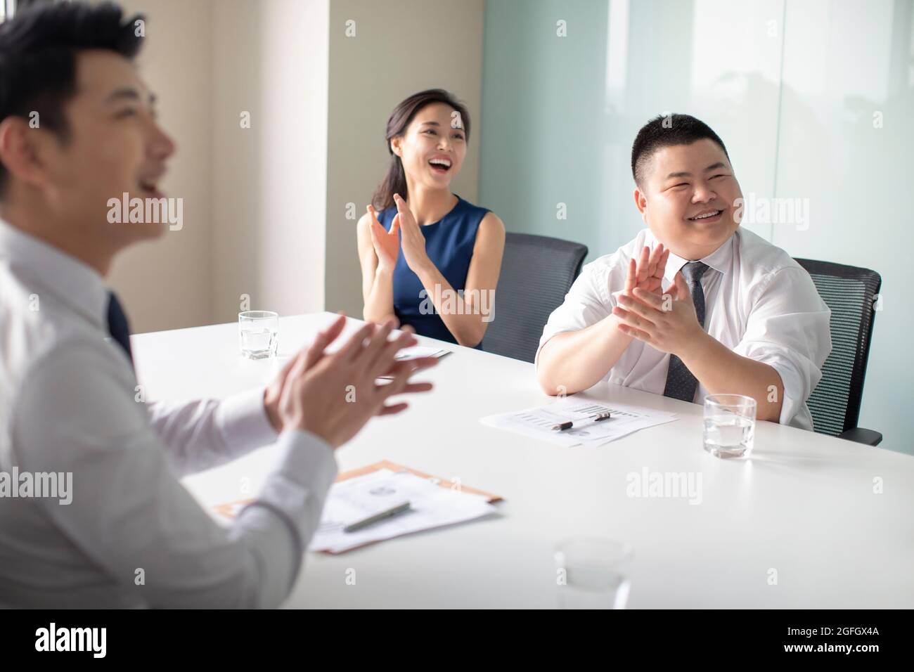 Confident business people clapping hands in office room Stock Photo - Alamy