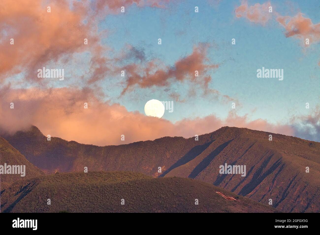 Full moon rising over the west maui mountains at sunset with pink puffy ...