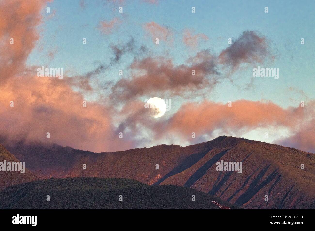 Full moon rising over the west maui mountains at sunset with pink puffy ...