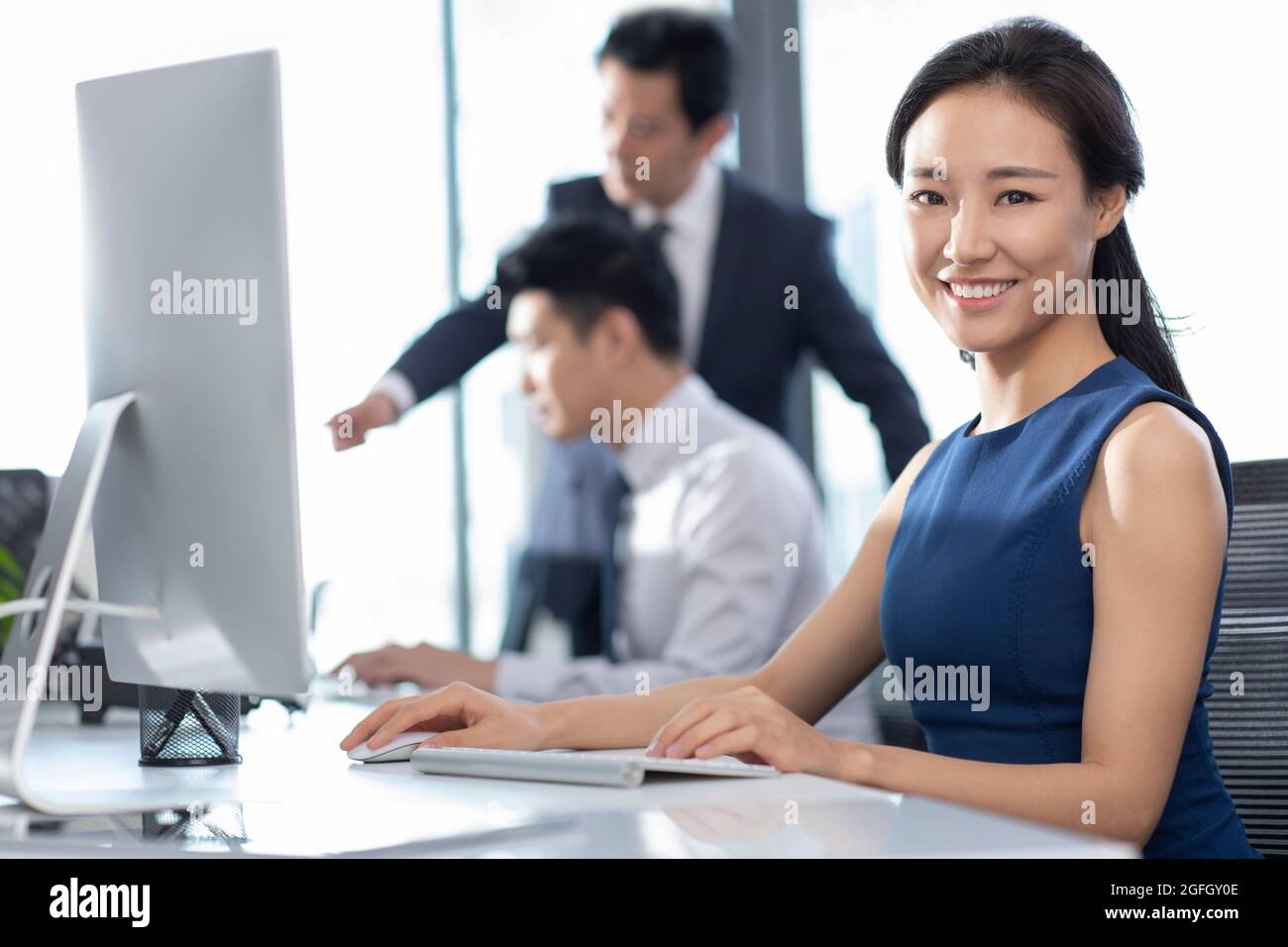Confident business people using computer in office Stock Photo - Alamy