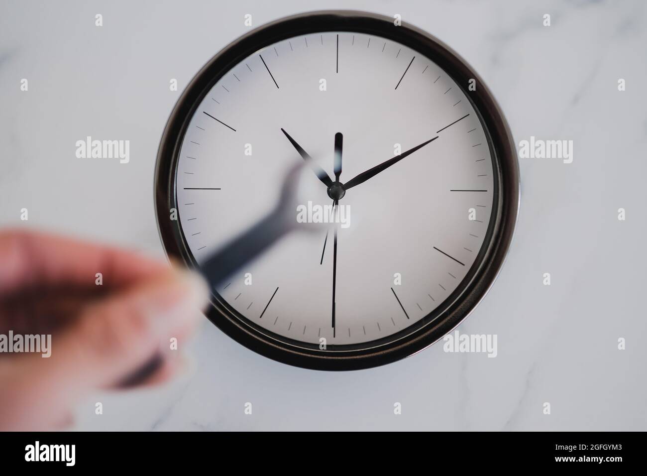 hand holding wrench in front of big clock shot at shallow depth of ...