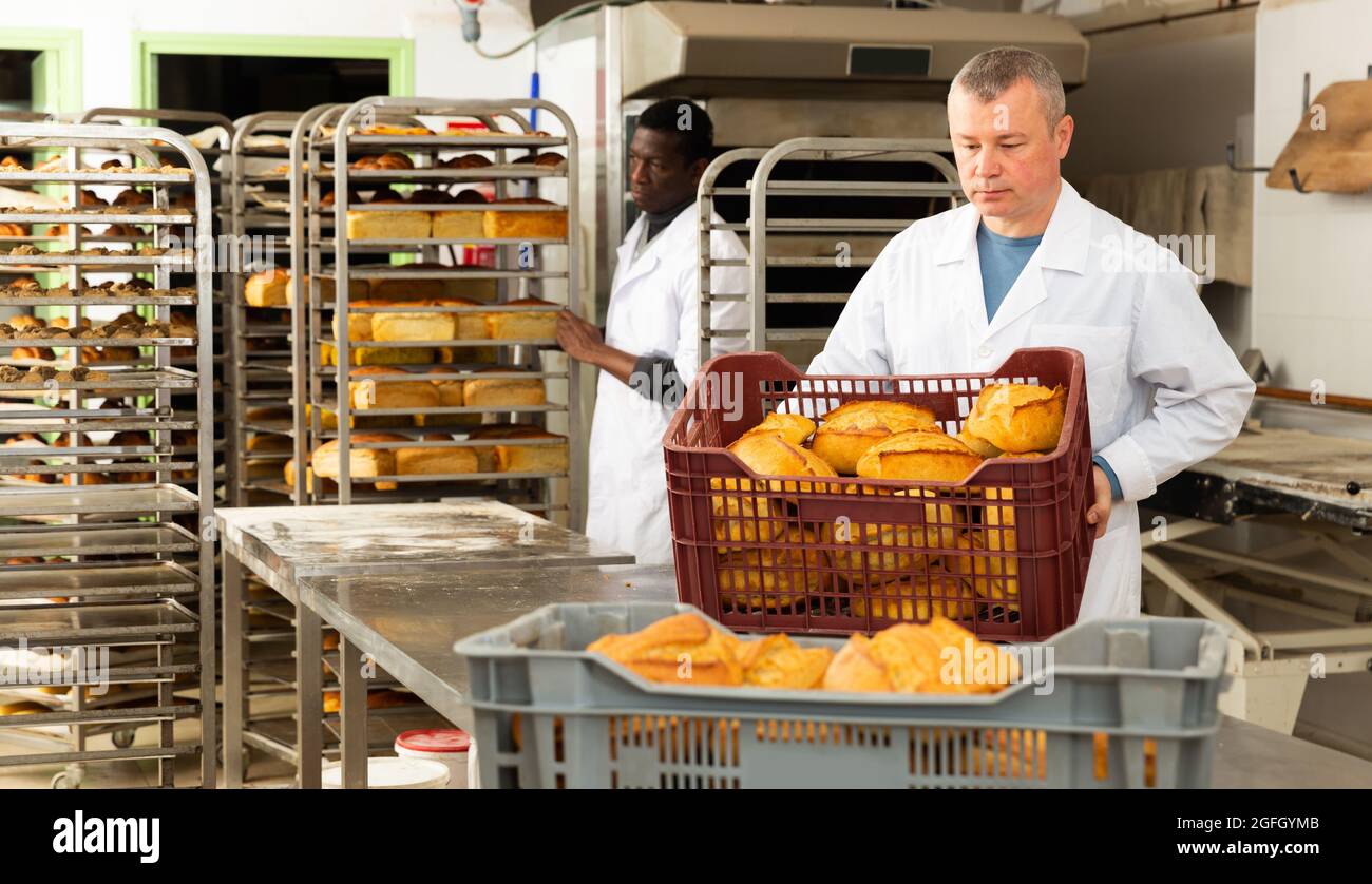 Two bakers arranging baked bread in bakery Stock Photo - Alamy