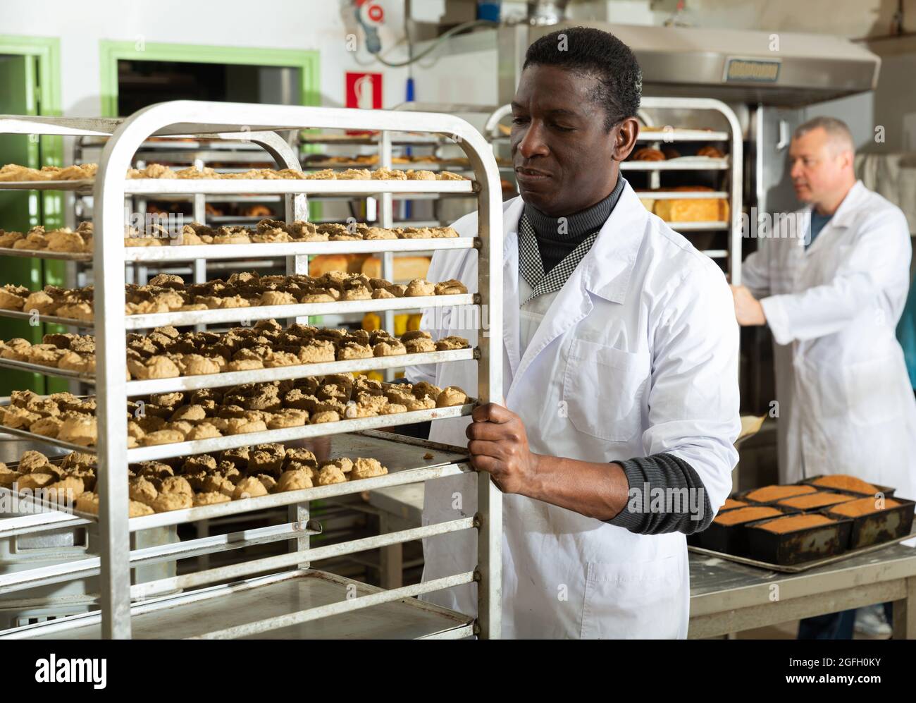 African baker carrying formed raw products on trolley Stock Photo - Alamy