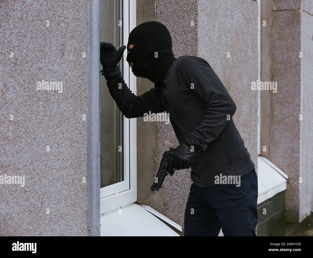 Armed thief looking through window Stock Photo - Alamy