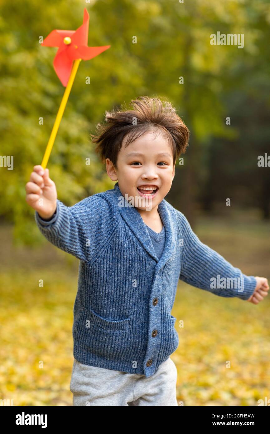 Little boy playing with paper windmill in woods Stock Photo - Alamy