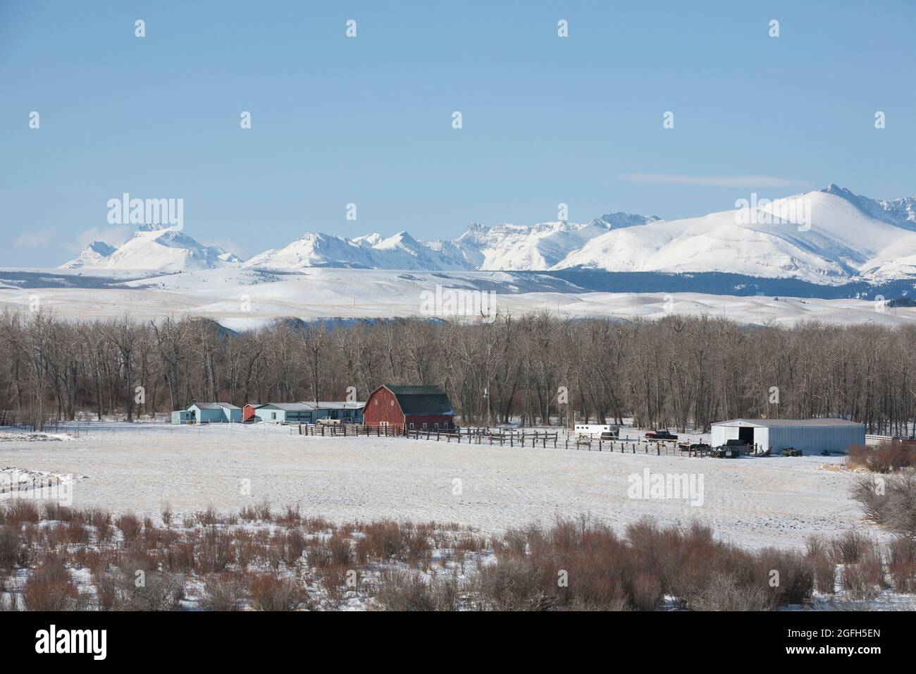 Blanketed with snow, a cattle ranch has an imposing background of the ...