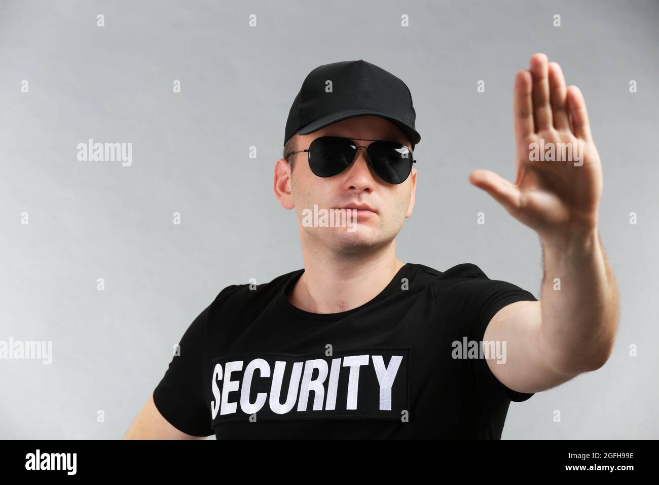 Male security guard on grey background Stock Photo - Alamy