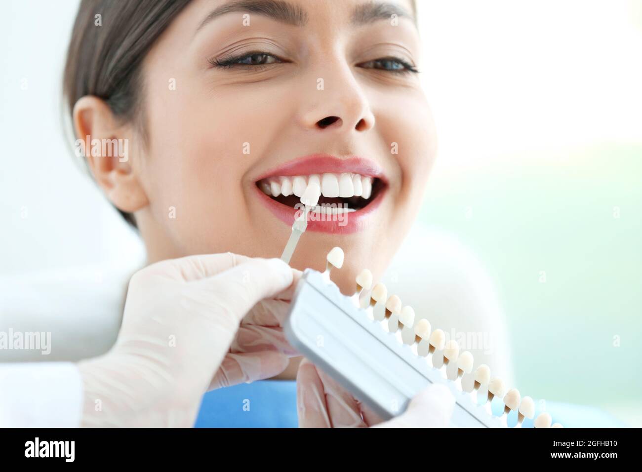 Dentist matching teeth colour in office Stock Photo - Alamy