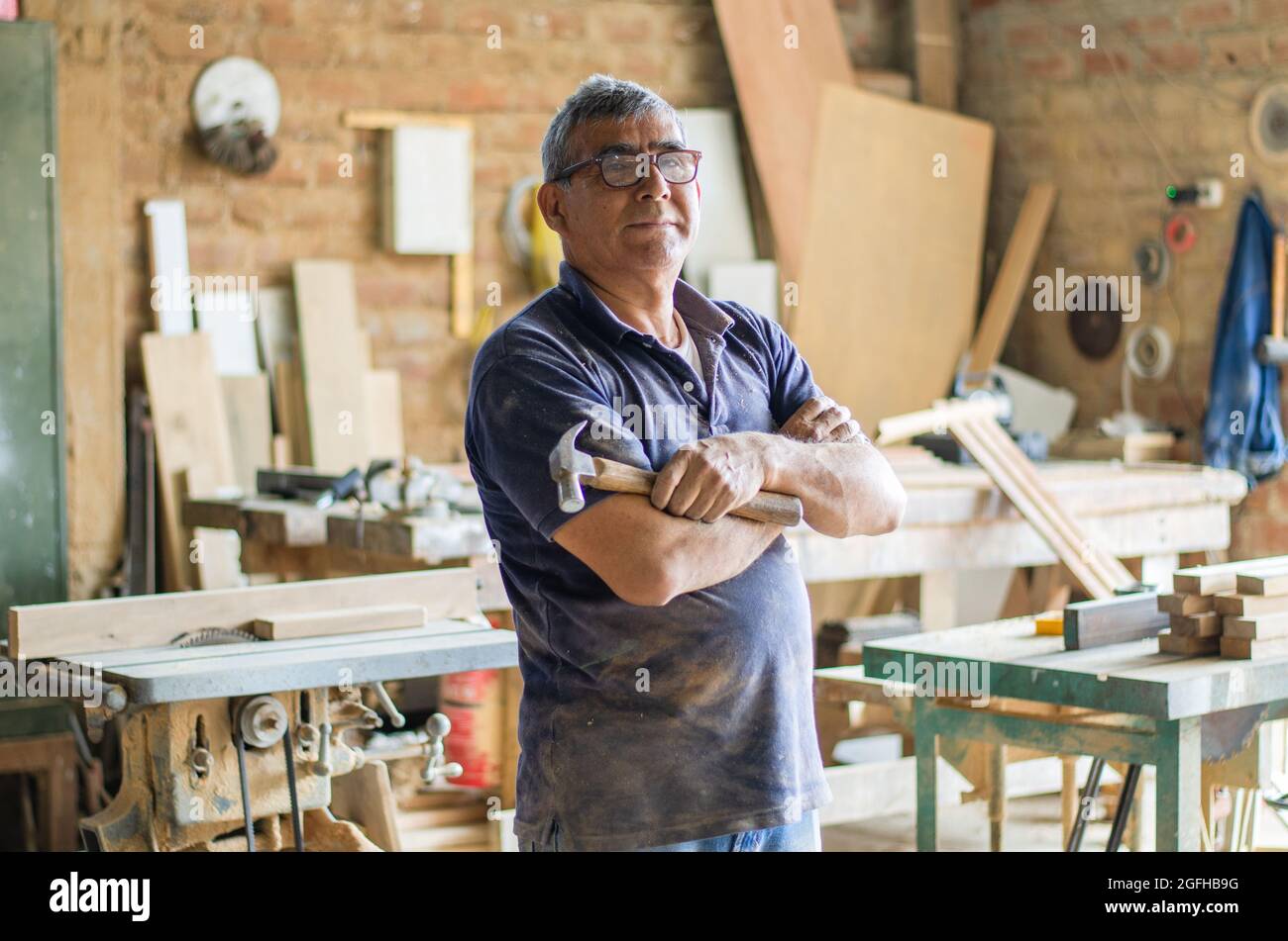Elderly carpenter posing with crossed arms in his workshop Stock Photo ...