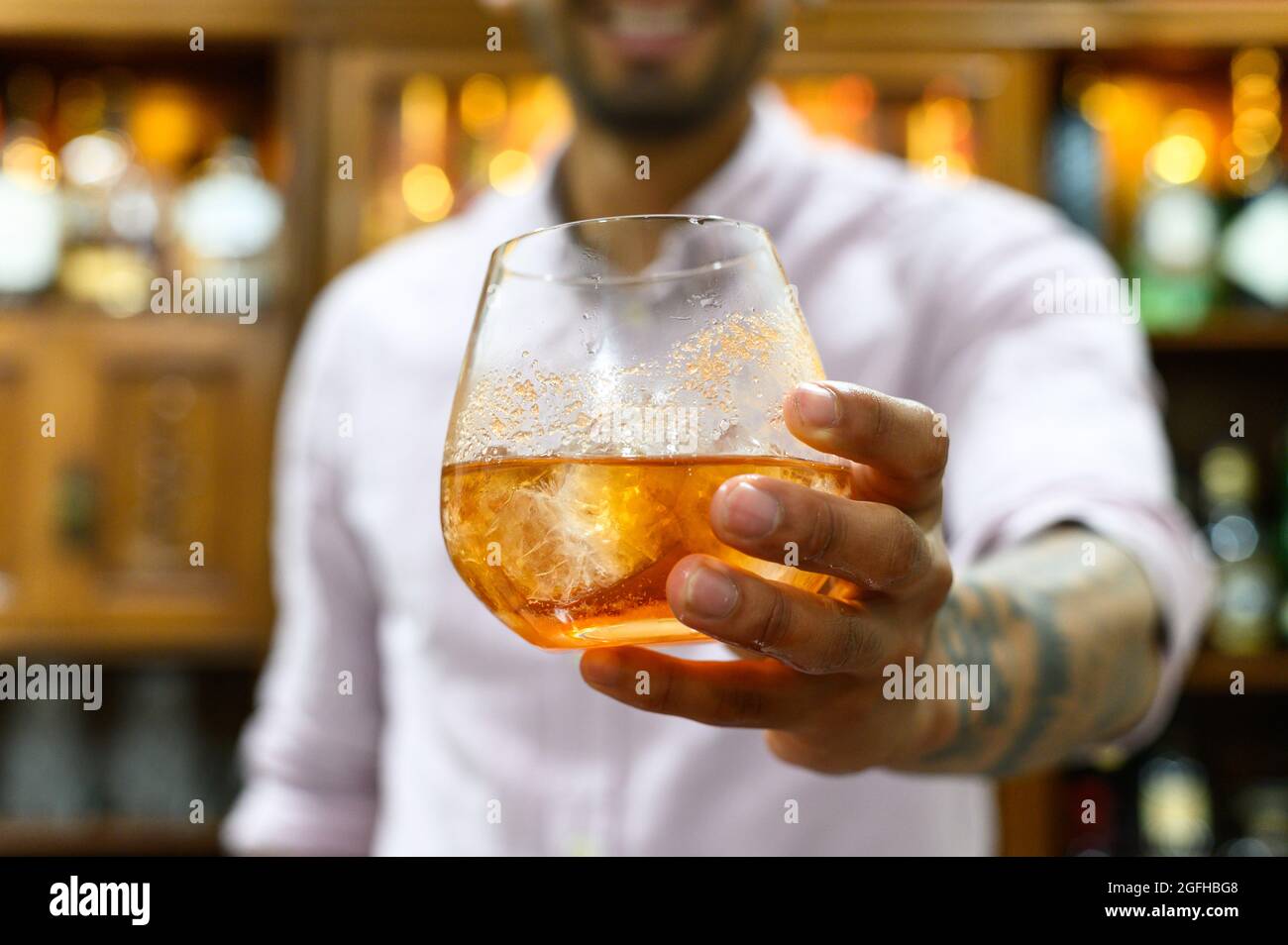 Male bartender serving whiskey in a clear crystal goblet Stock Photo ...