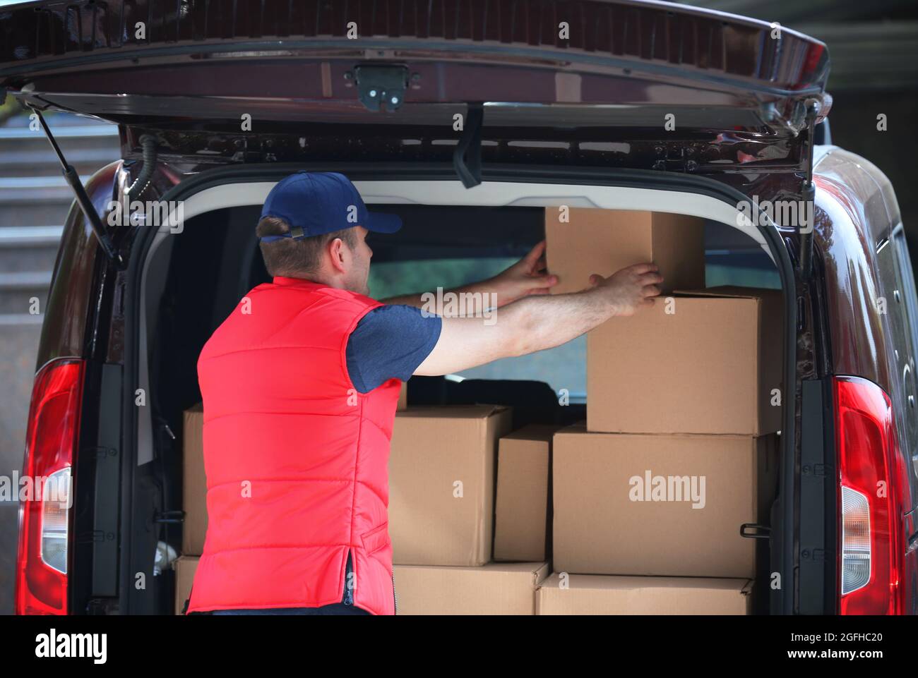 Young male deliverer loading boxes into car Stock Photo - Alamy