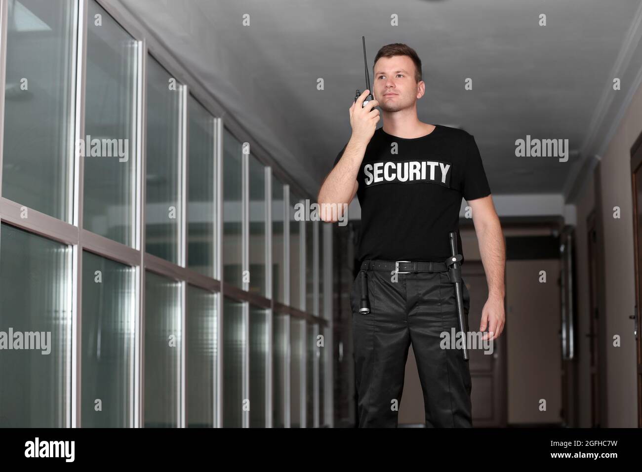 Security man in corridor using portable radio Stock Photo - Alamy