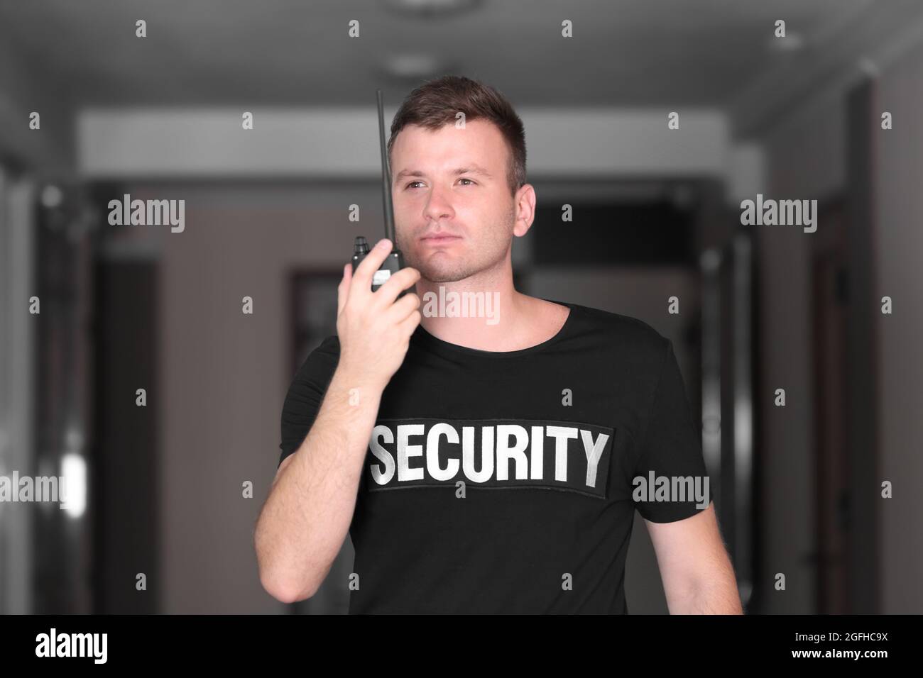 Security man standing indoors and using portable radio Stock Photo - Alamy