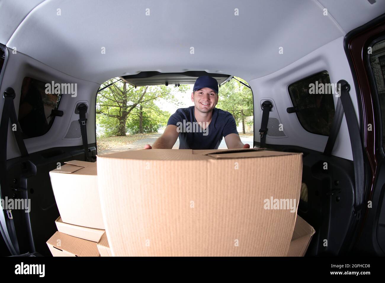 Young male deliverer loading boxes into car Stock Photo - Alamy